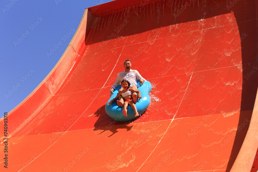 Family going down a water slide at a water park in summer. Father and ...