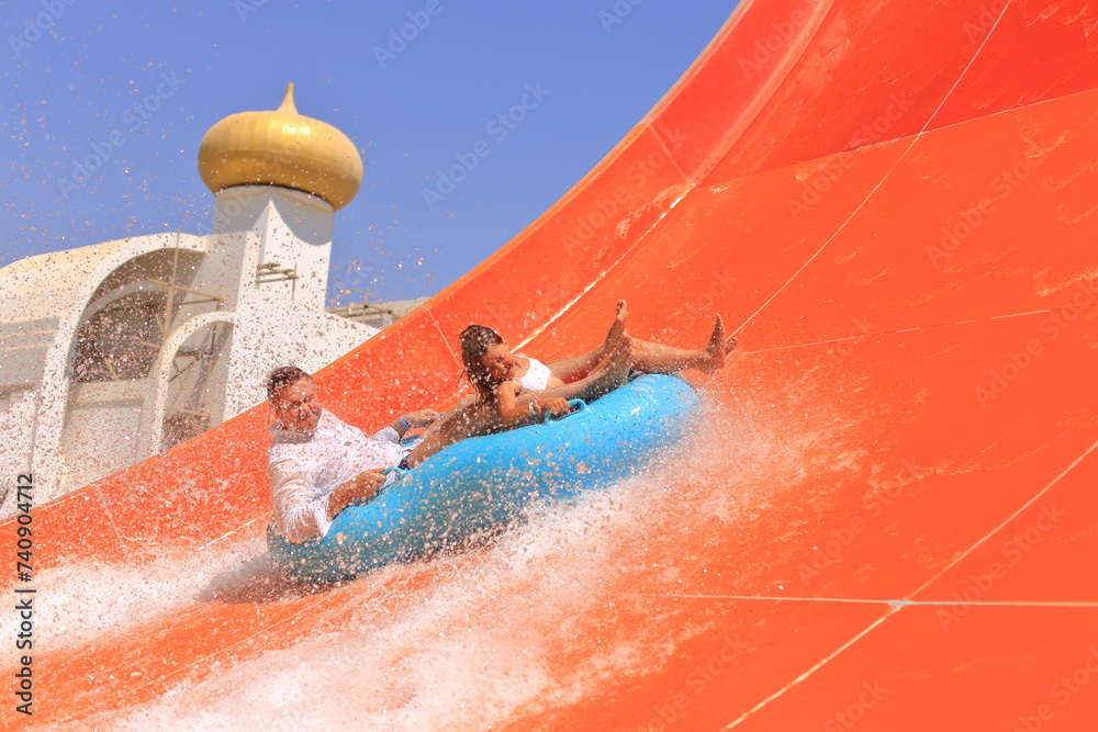 Family going down a water slide at a water park in summer. Splashes of ...