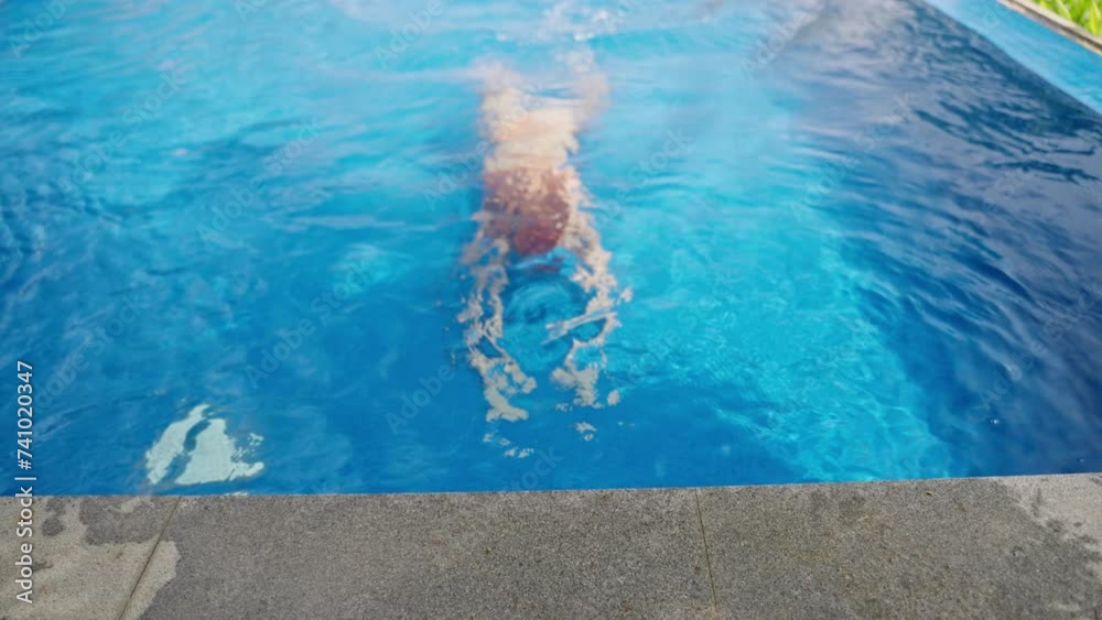 Elegant woman emerges from clear blue infinity pool in tropical resort ...