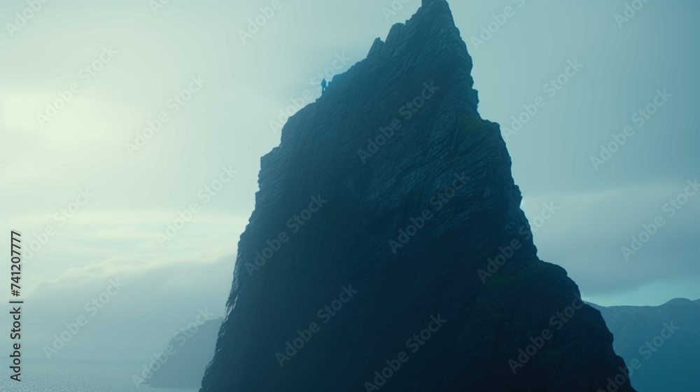 A large, dark, jagged cliff rises steeply from the sea, dominating the ...