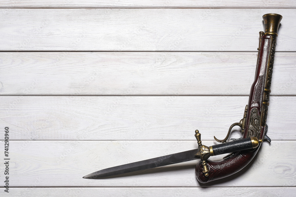 Vintage retro style dagger sword and musket gun on the white wooden ...