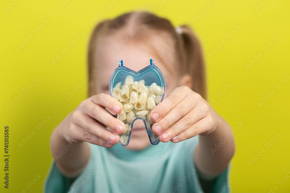 A model of an artificial tooth in the hands of a little girl of seven ...