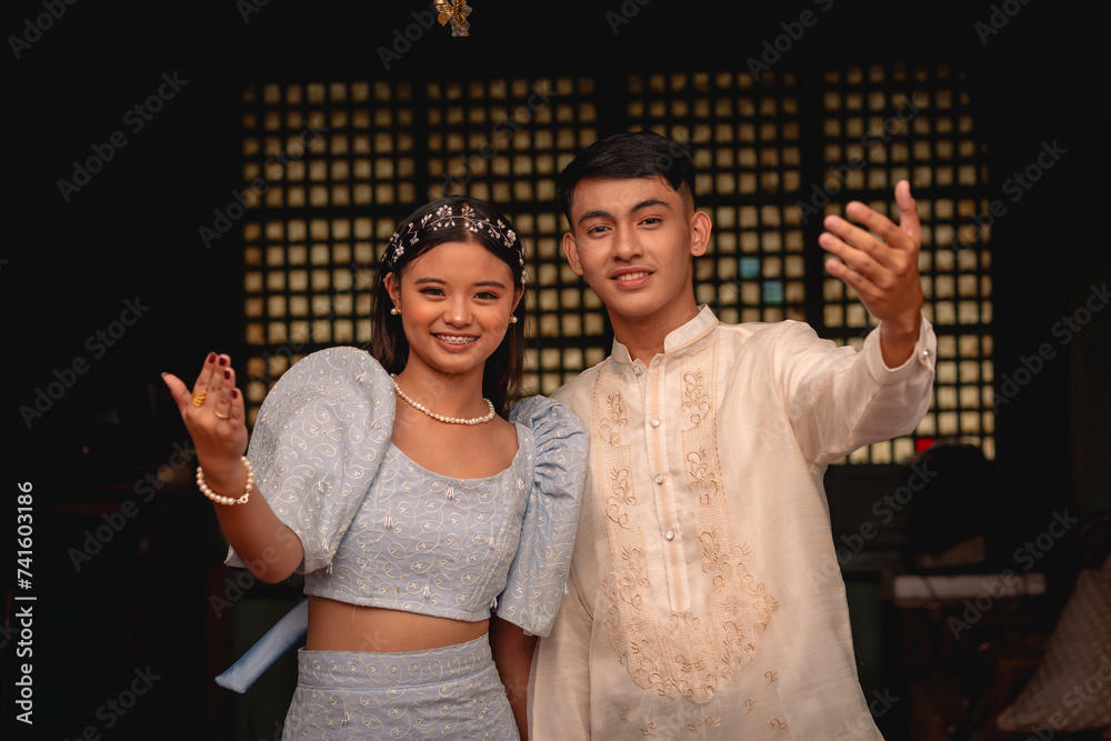 A young friendly couple in Filipino traditional clothing inviting you ...