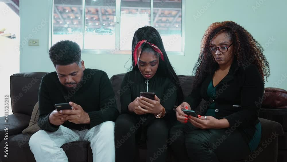 Three people staring at their phones seated on sofa indoors hypnotized ...
