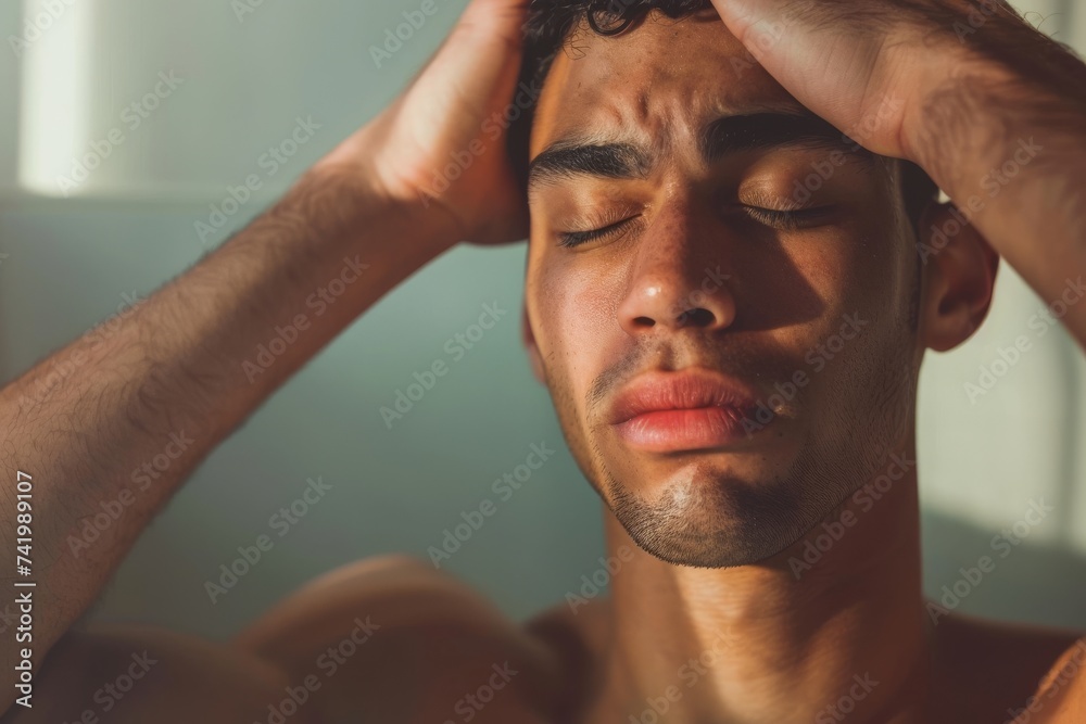 A weary man's face reveals the weight of his thoughts as he holds his ...