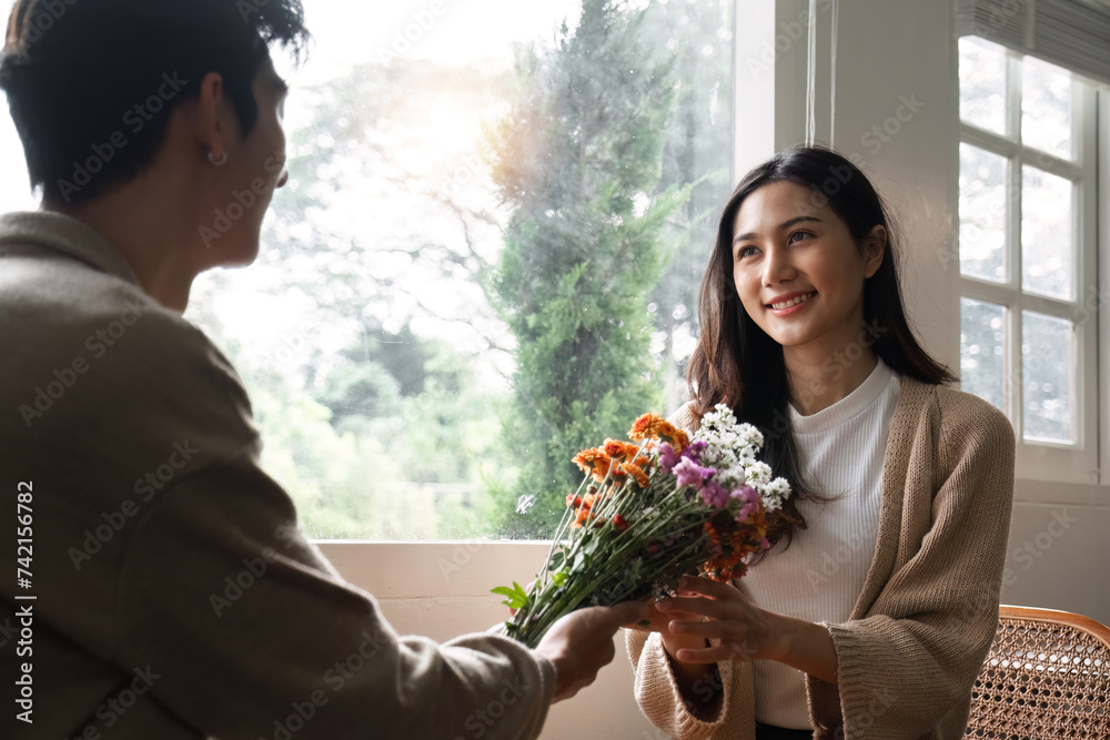 A young Asian couple gives flowers to each other on their anniversary ...