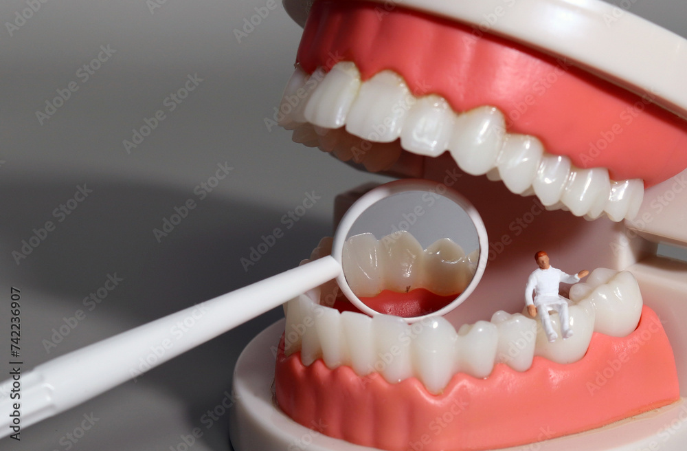 Miniature dentist examining teeth with dental mirror. Miniature of a ...