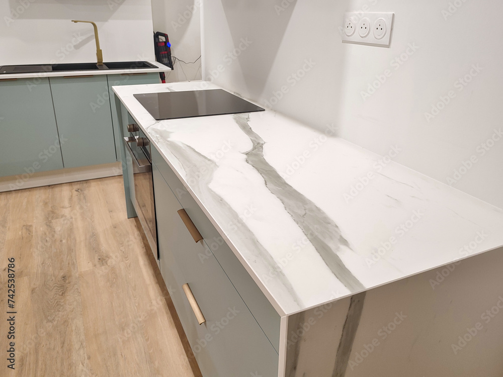 Marbled ceramic countertop, set on a blue-green kitchen cabinet with ...