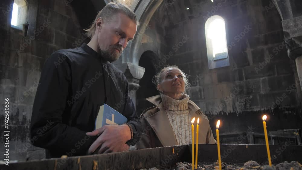 A young attractive priest holding a bible standing with a pretty woman ...