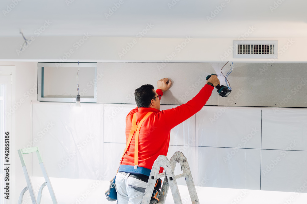 Plasterboard worker installs a plasterboard wall on the kitchen ...