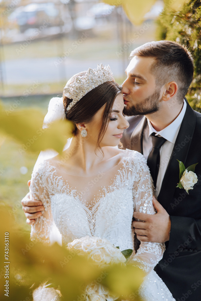 A young bride and groom tenderly embrace in the rays of the autumn sun ...