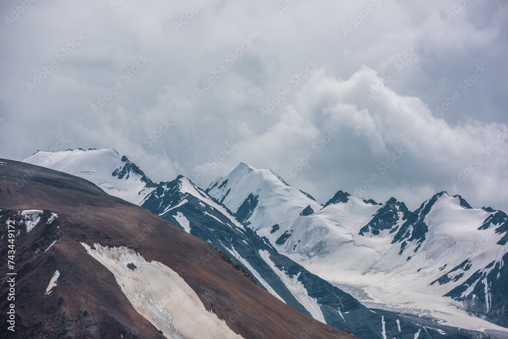 Dramatic view to large rock mountain range with snow-capped pinnacle in ...
