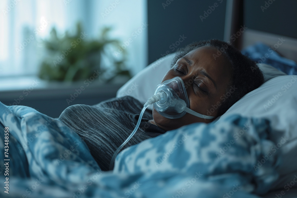 Foto de Middle aged african woman wearing oxygen mask sleeping in bed ...