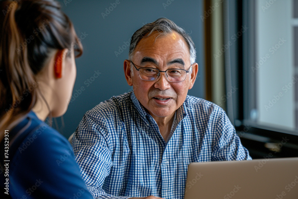 Mature Latin manager mentor talking to young Asian female coworker showing online project ...