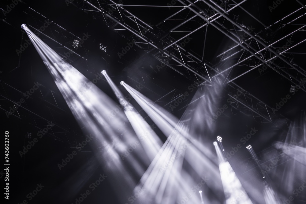 Intense stage lights beaming from a metal truss structure in a dark ...