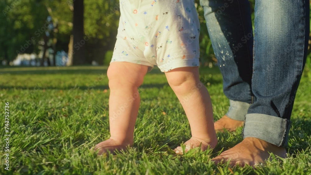 Walking children's bare feet on a green lawn close-up. Child learns to ...