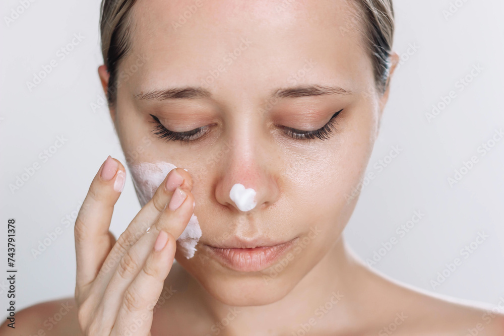 Young caucasian woman touching face with her hand applying a ...