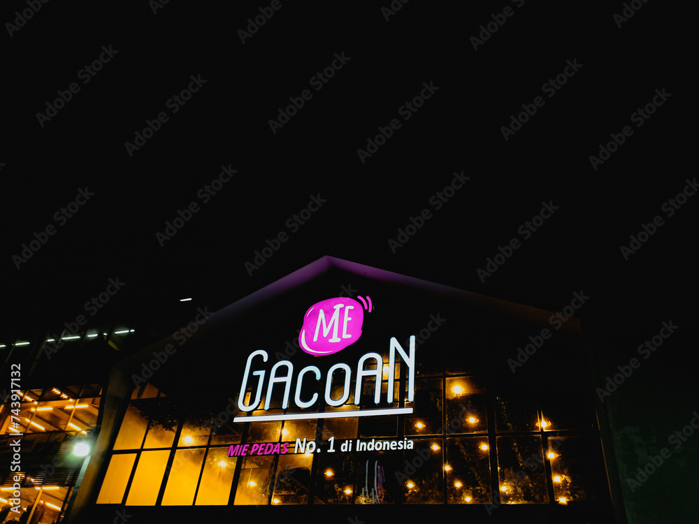 Outlet exterior of Mie Gacoan with blue pink logo on top. Number one ...