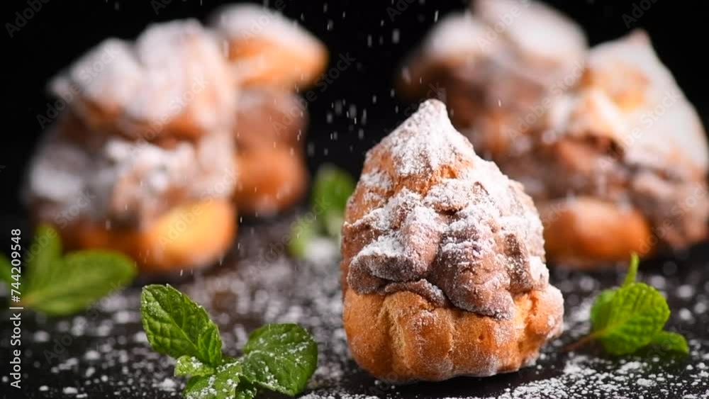 Profiteroles or cream puff with filling, falling powder sugar topping ...
