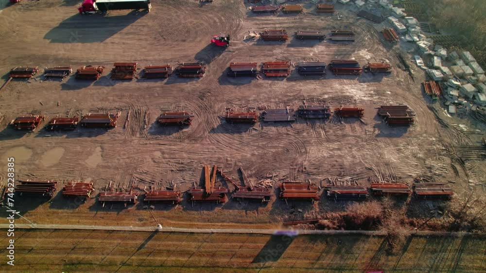 Overview aerial of a forklift driver loading steel bars for a red Semi ...