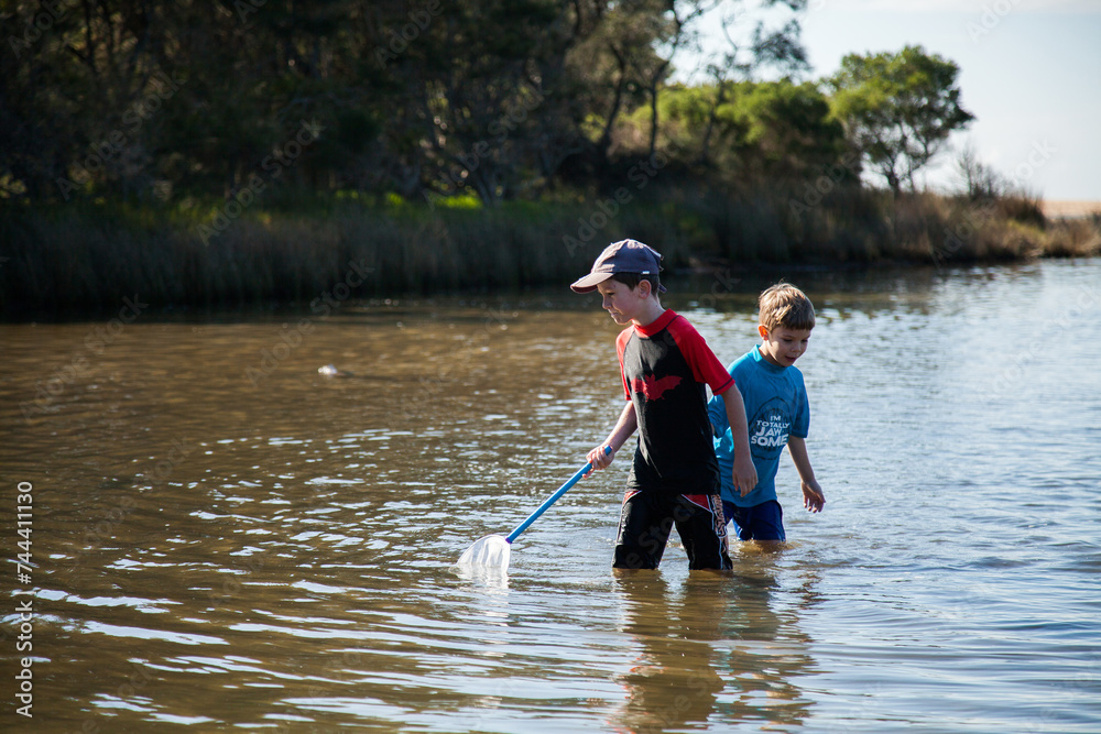Two boys wading and playing where the river meets the sea Stock Photo ...
