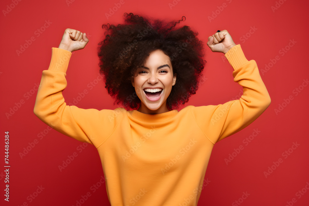 Young woman cheering with arms raised in victory gesture in front of ...