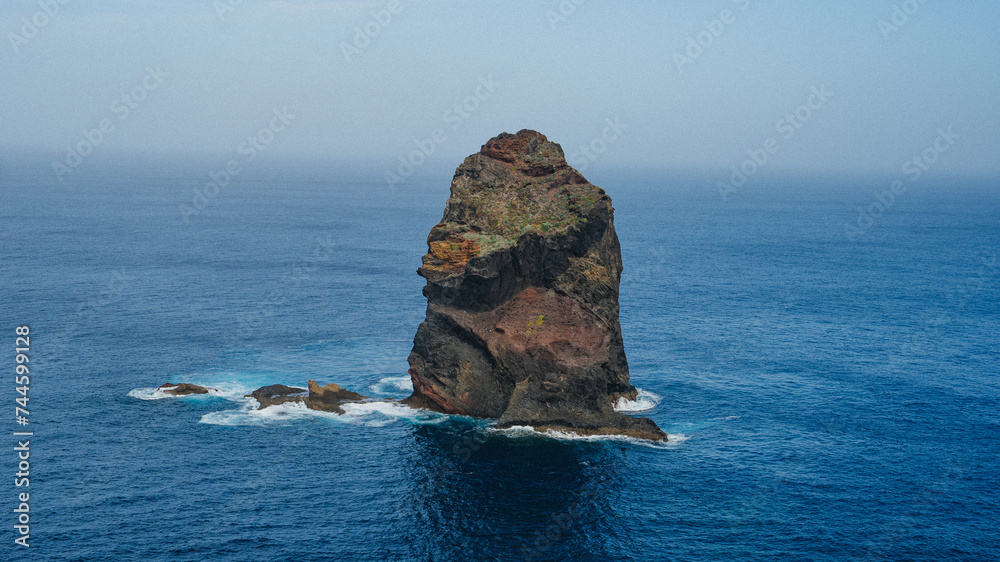 Red rock pillar protruding out of the Atlantic Ocean at the Ponta de ...