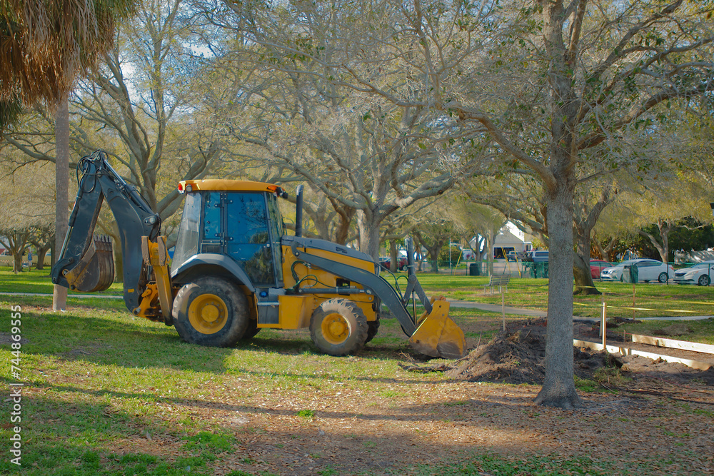 Profile of yellow and black backhoe in the grass and wood frames for ...