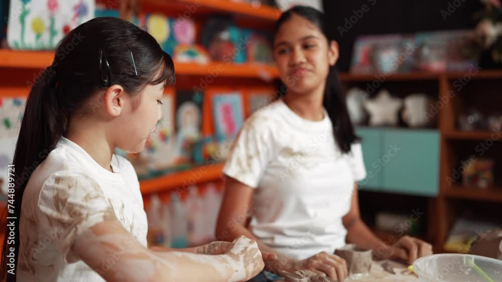 Caucasian smart high school girl modeling cup of clay while diverse ...