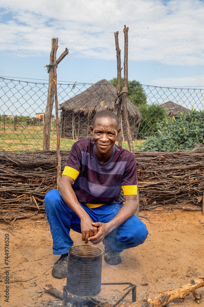 village african man in the yard, cooking in the outdoors kitchen, in ...