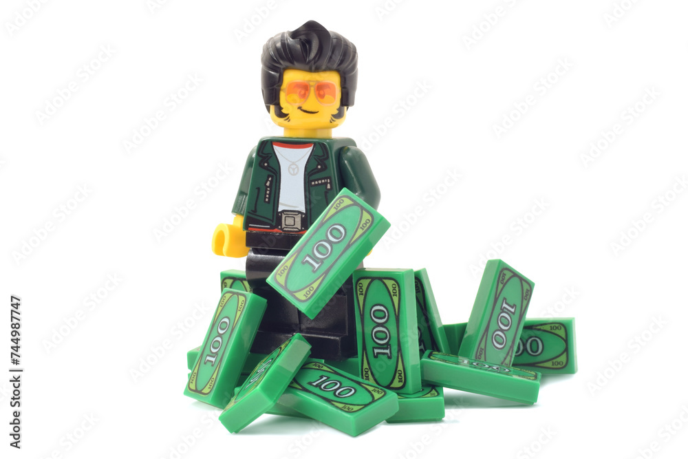 Lego minifigure of happy male is counting his money green banknotes ...