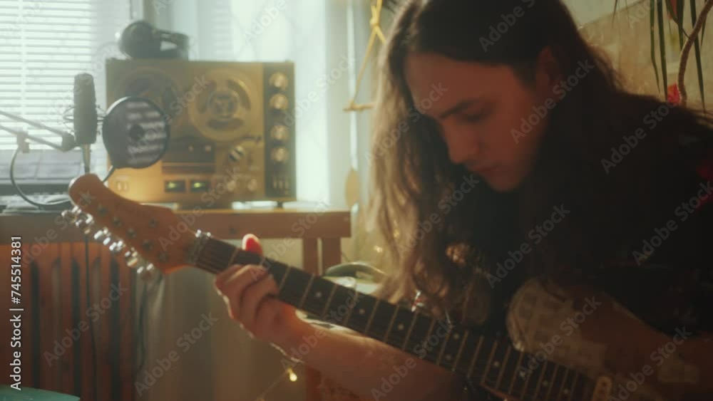 Vidéo Stock Young creative man playing the guitar on a couch in living ...