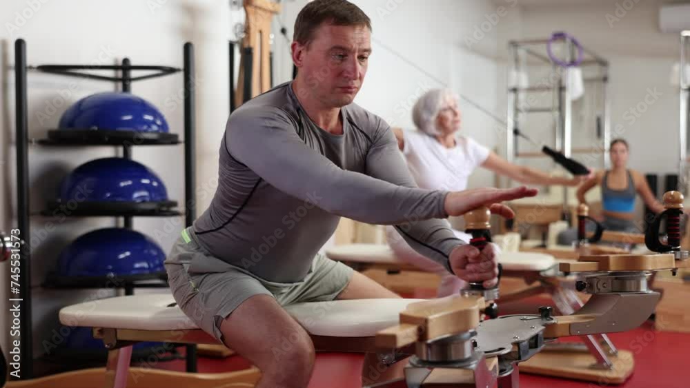 In gym, male performs Pilates exercises to lose weight and bring ...