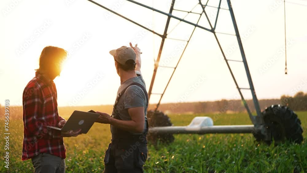 Agriculture.Teamwork of farmers in corn field. Irrigation system.Work ...