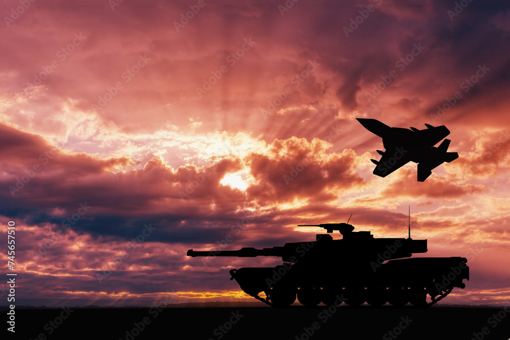 Silhouettes of a battle tank and a flying military aircraft against a ...