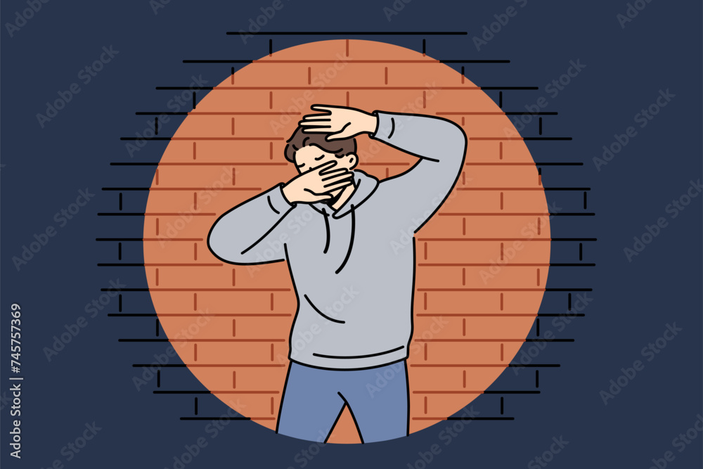 Man criminal in light of police lantern stands near brick wall and ...