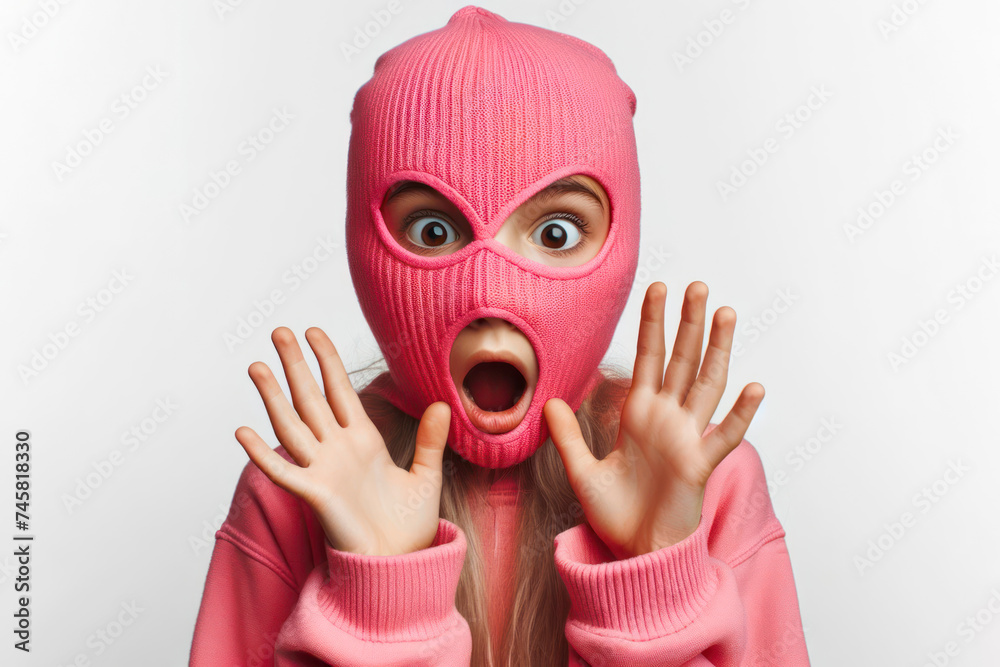 girl in a pink robber mask with a shocked expression isolated on solid ...