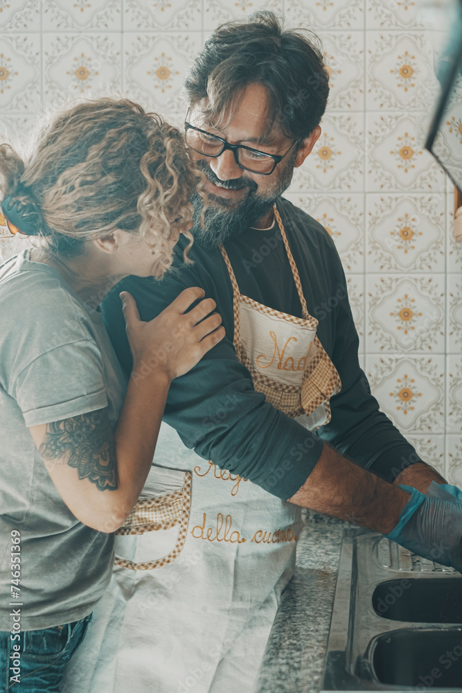 One man helping wife in housework job washing the dishes in the kitchen ...