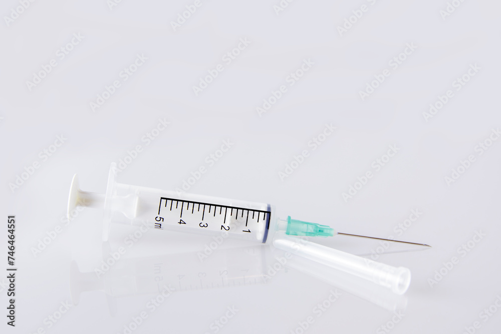 Medical syringe with its needle and cap removed, it is lying on white ...