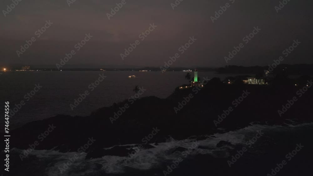 Dusk fades to night over a cliffside lighthouse, guiding with its ...
