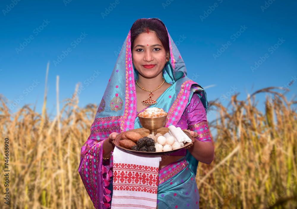 Woman wearing traditional costume holding a tray full of Magh Bihu ...