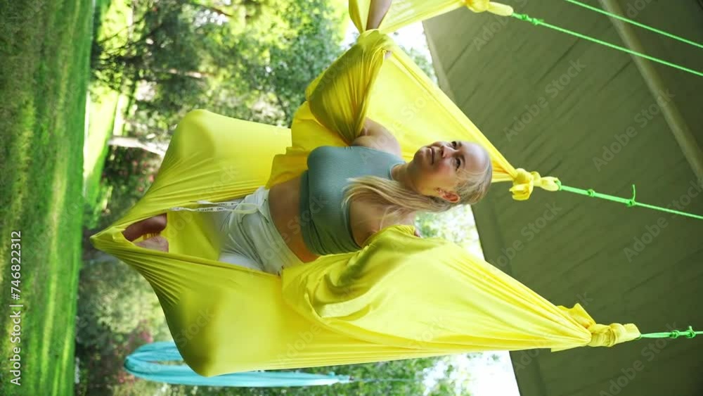 Woman yoga aero air inverted asanas in hammock in public park. Sport ...