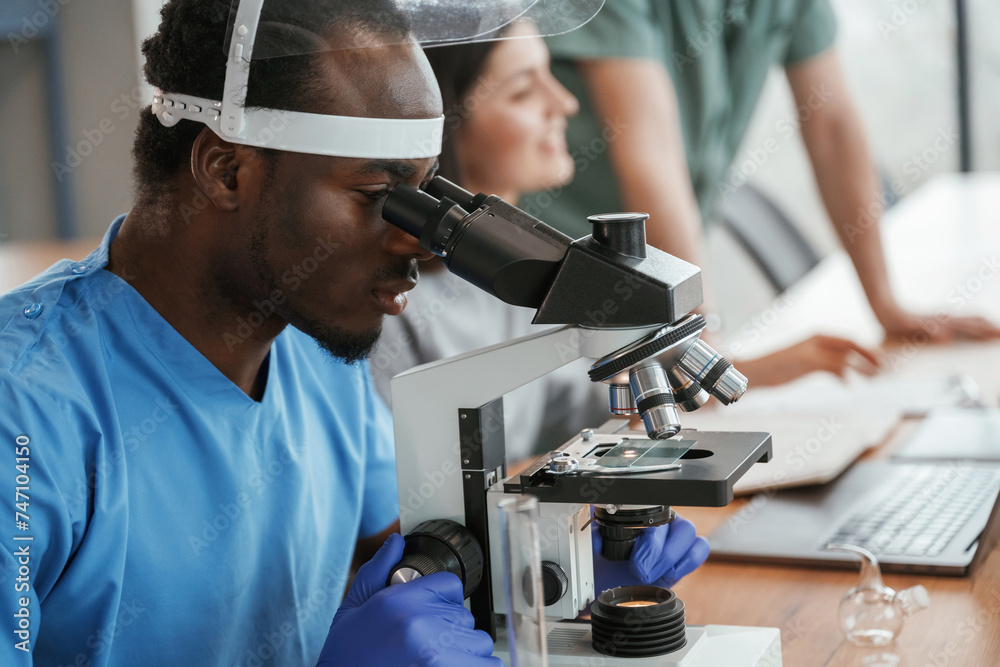 Working in a lab with test tubes and microscope. Group of doctors are ...