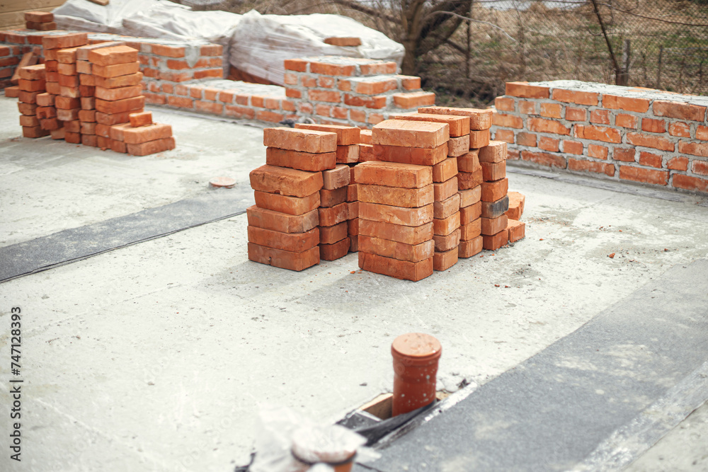 Stack of red bricks on concrete foundation, process of house building ...