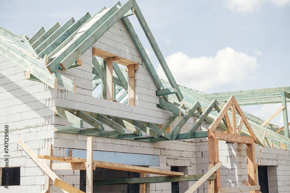 Unfinished modern farmhouse building. Wooden roof framing of mansard ...