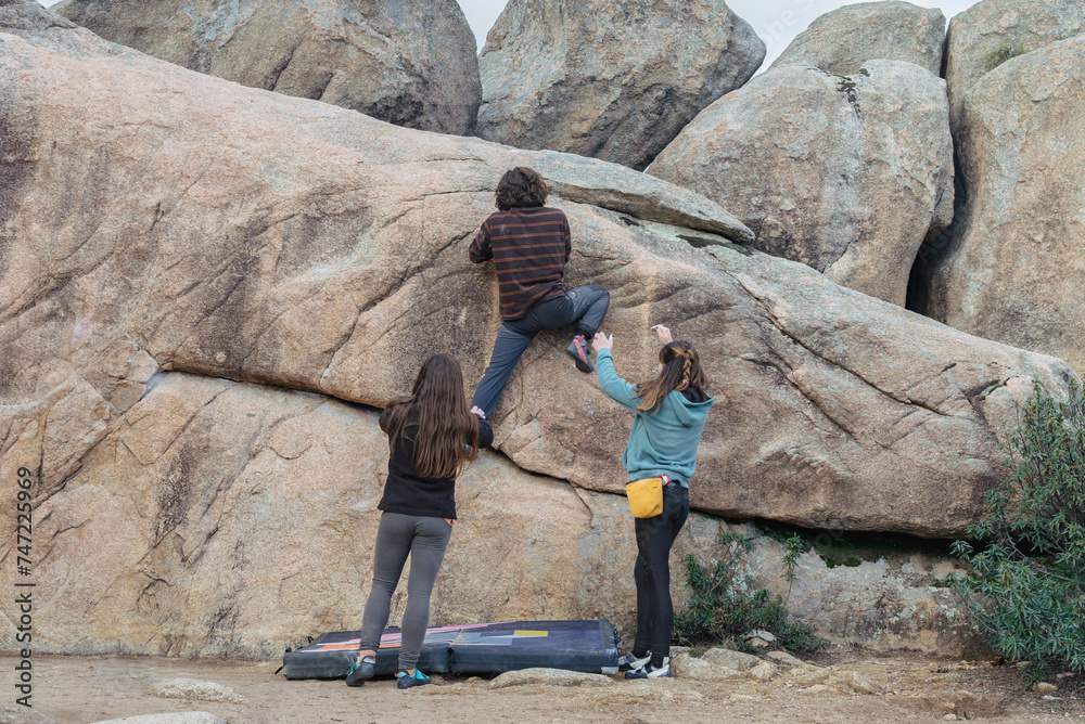 Anonymous Climbers work together on a complex boulder problem, with two ...