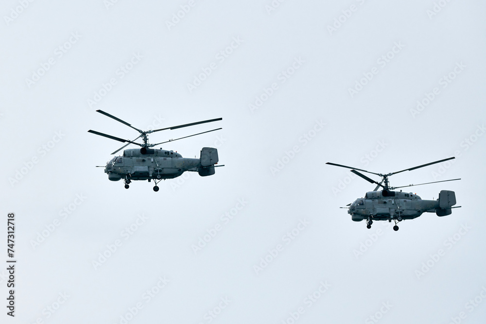 Two Russian military helicopters armed with missiles flies in blue sky ...