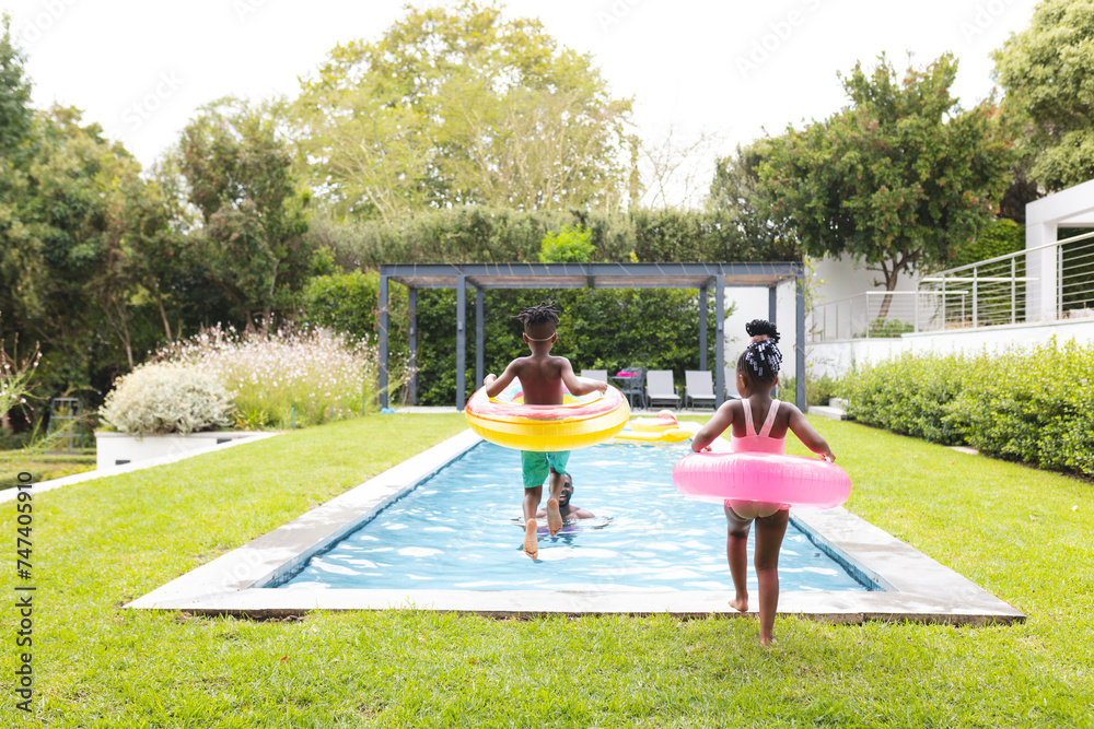 African American brother and sister with colorful floaties prepare to ...