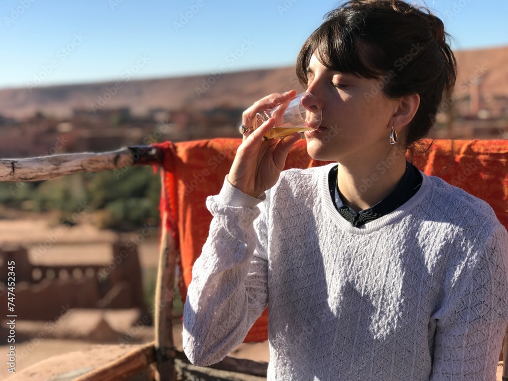 cute young girl drinking mint tea on a terrace in the adobe village of ...