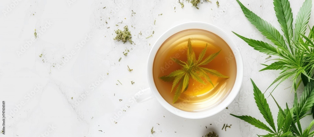 A cup of hemp tea with a marijuana leaf floating in it, placed on a ...